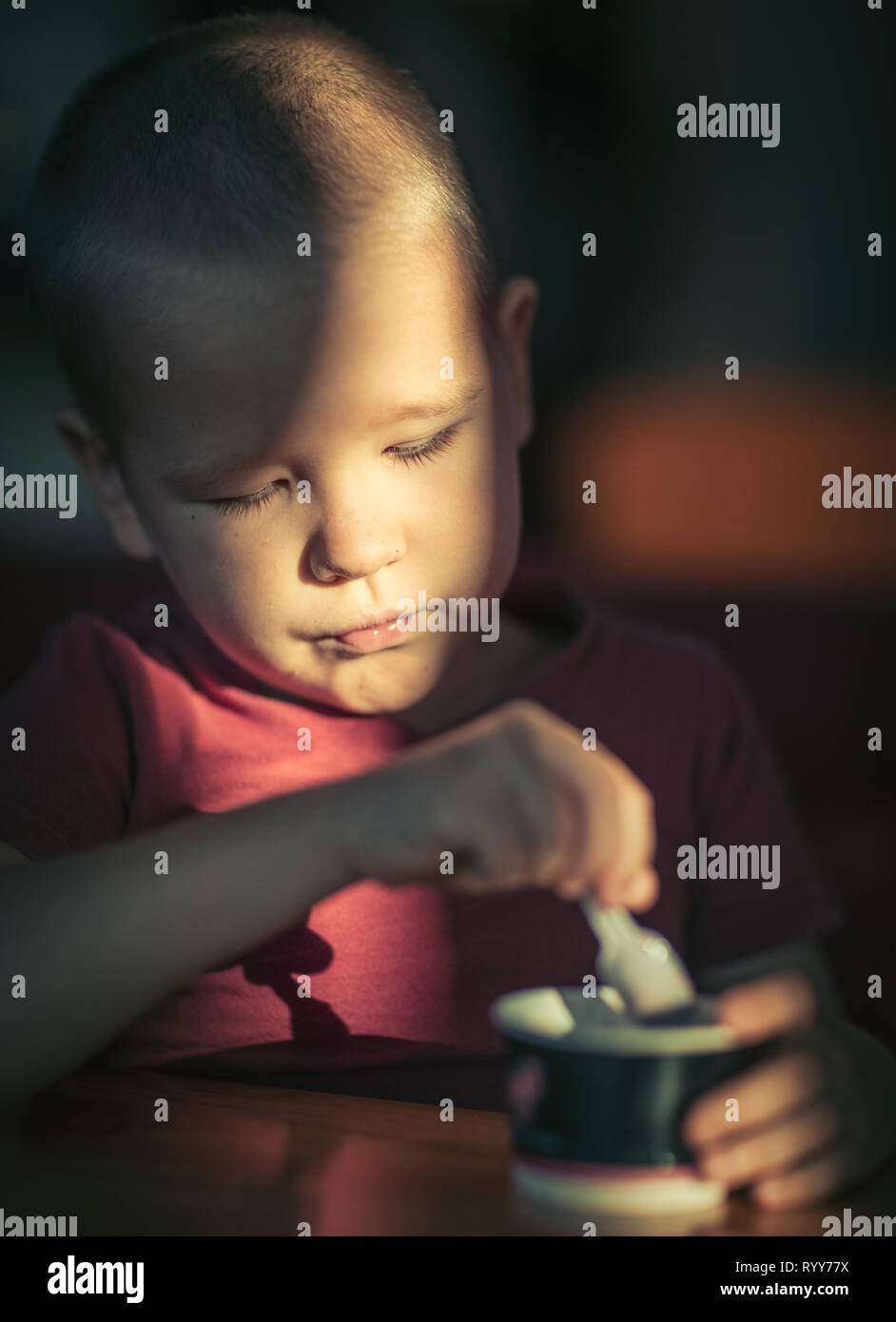 Portrait of a boy eating ice cream. High contrast hard light portrait ...