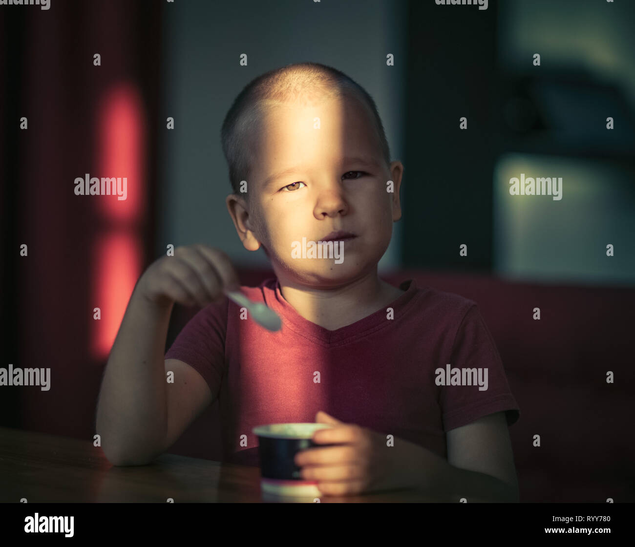 Portrait of a boy eating ice cream. High contrast hard light portrait ...