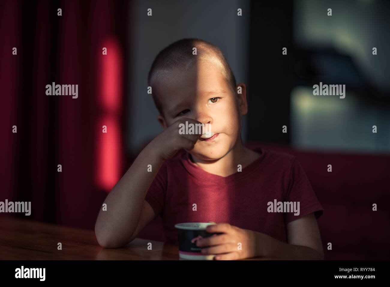 Portrait of a smiling boy eating ice cream. High contrast hard light ...