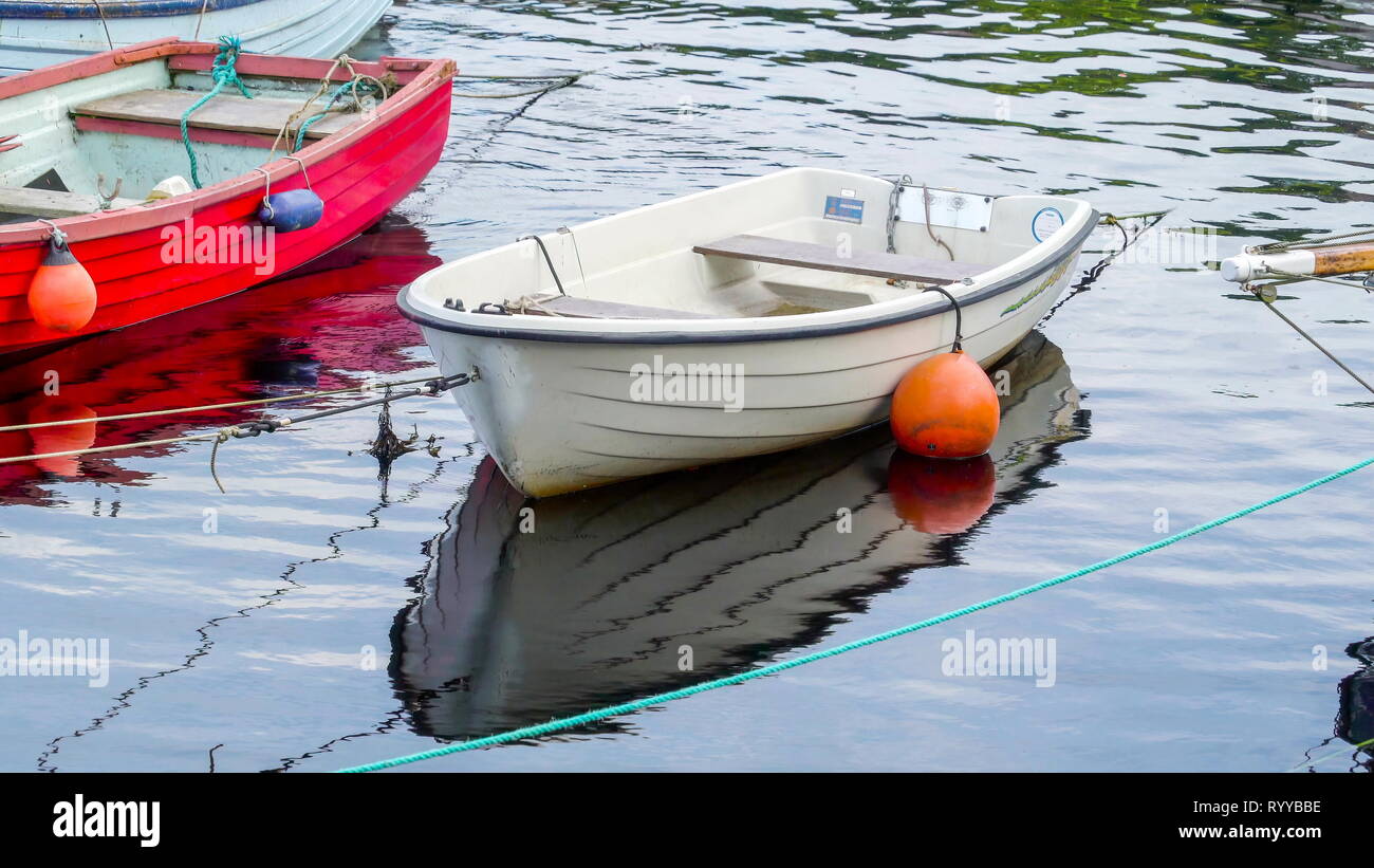 Two small boats floating on the river the white one with a red bayou on ...