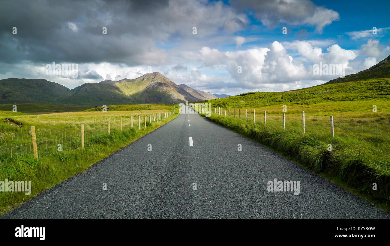 Small road in the Connemara National Park with the green field on the ...