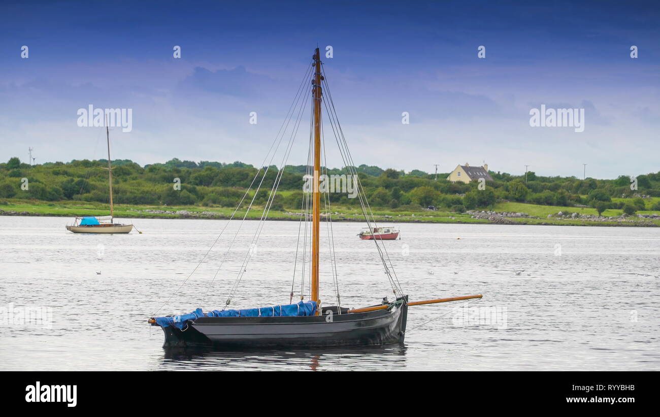 A small sailboat floating on the sea along with other boat floating in ...
