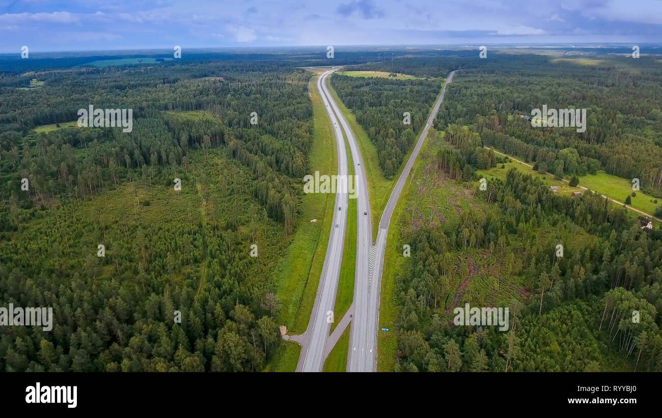 Aerial view of the road and the forest with the tall trees and the long ...