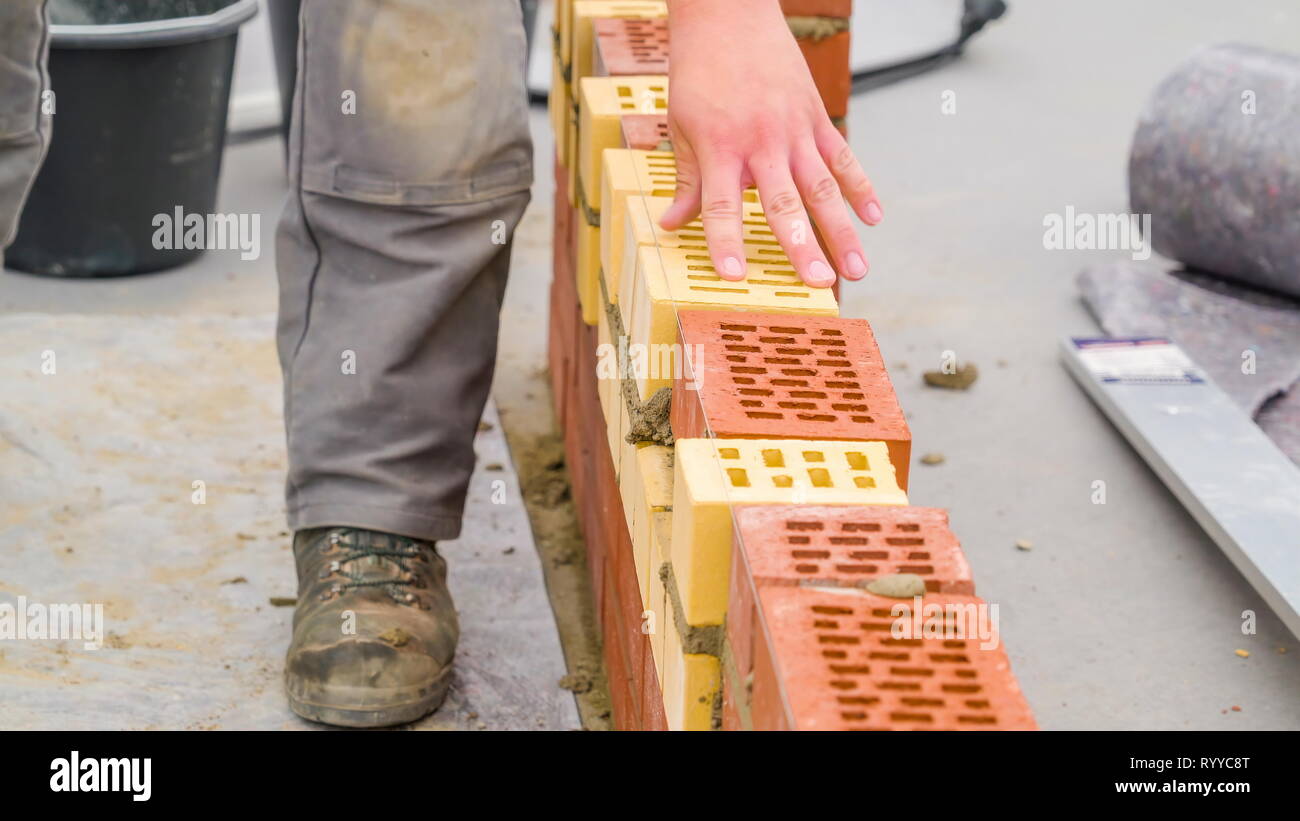A worker putting up a pile of bricks on the ground with the use of a ...