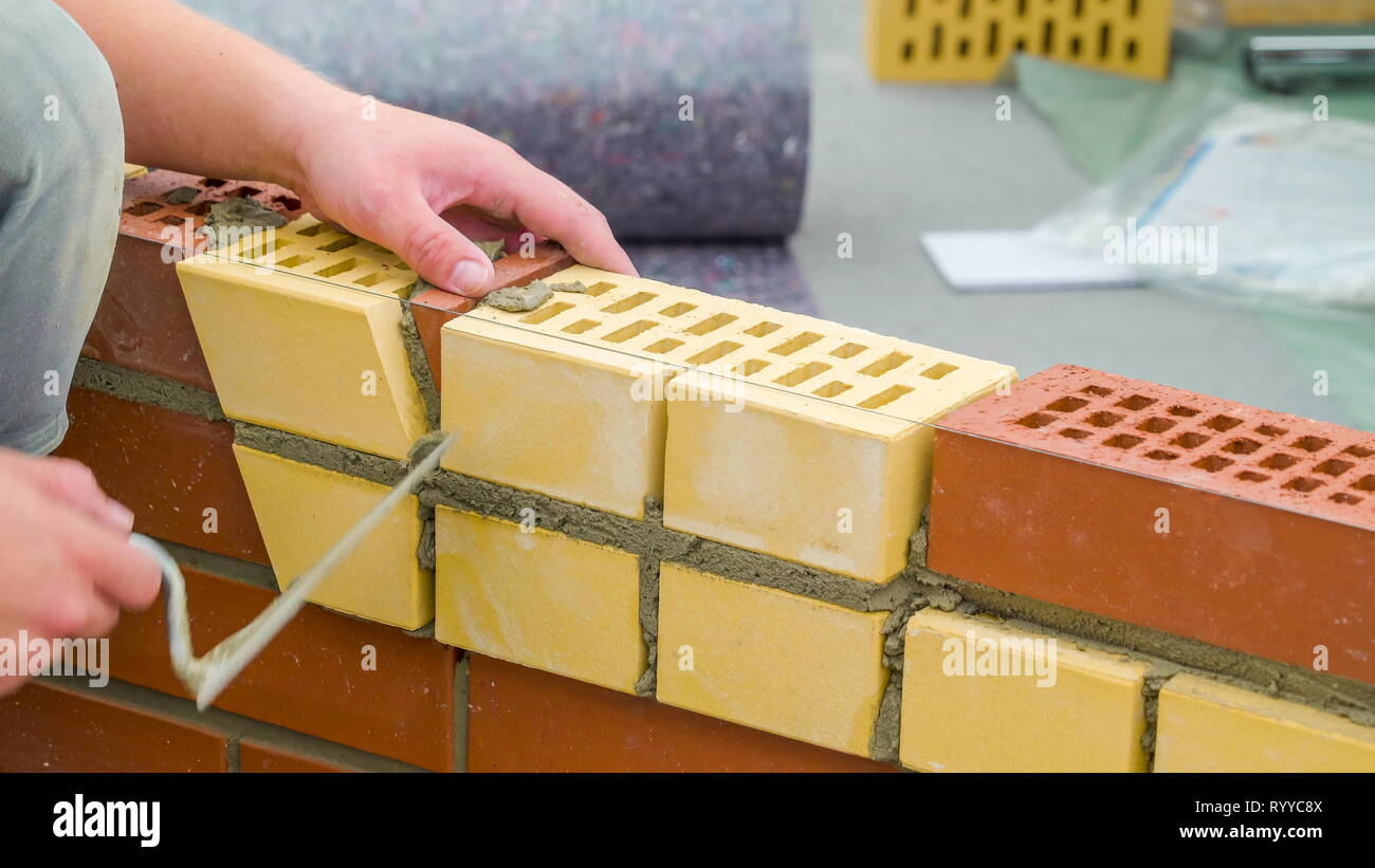 A worker man inserting a small piece of brick in between the big yellow ...