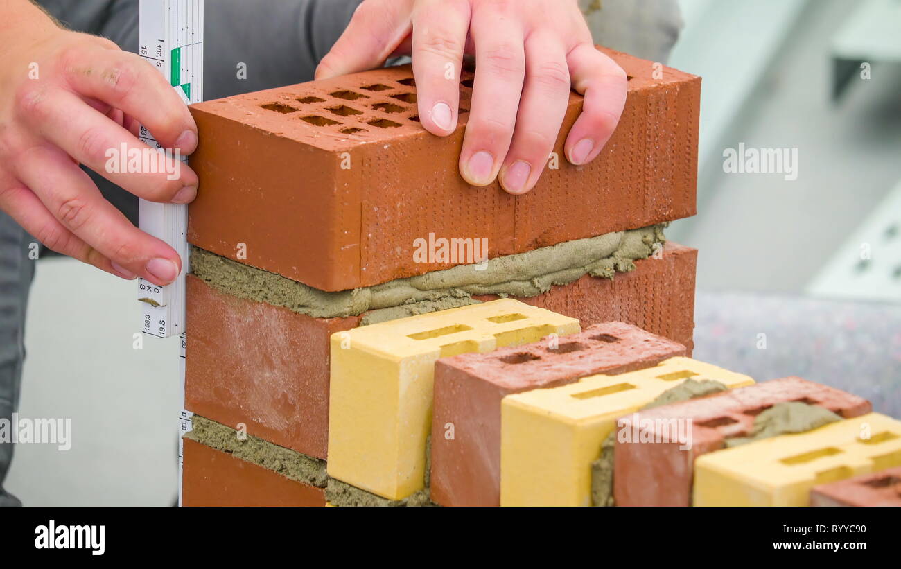 Piling up of bricks using the cement to paste the worker uses a ruler ...