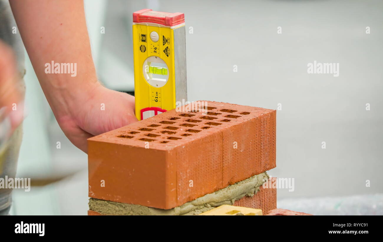 Aligning the bricks using the ruler with the cement as a paste to make ...