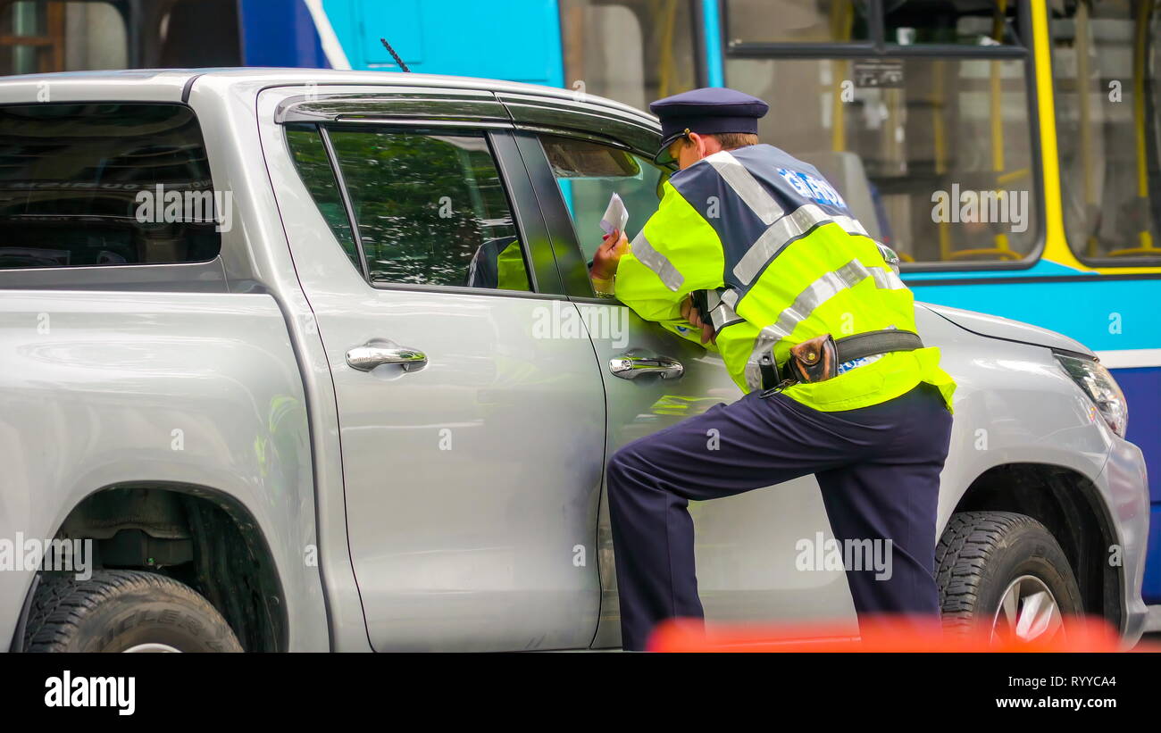 A traffic enforcer talking to a man inside the car in the streets of ...