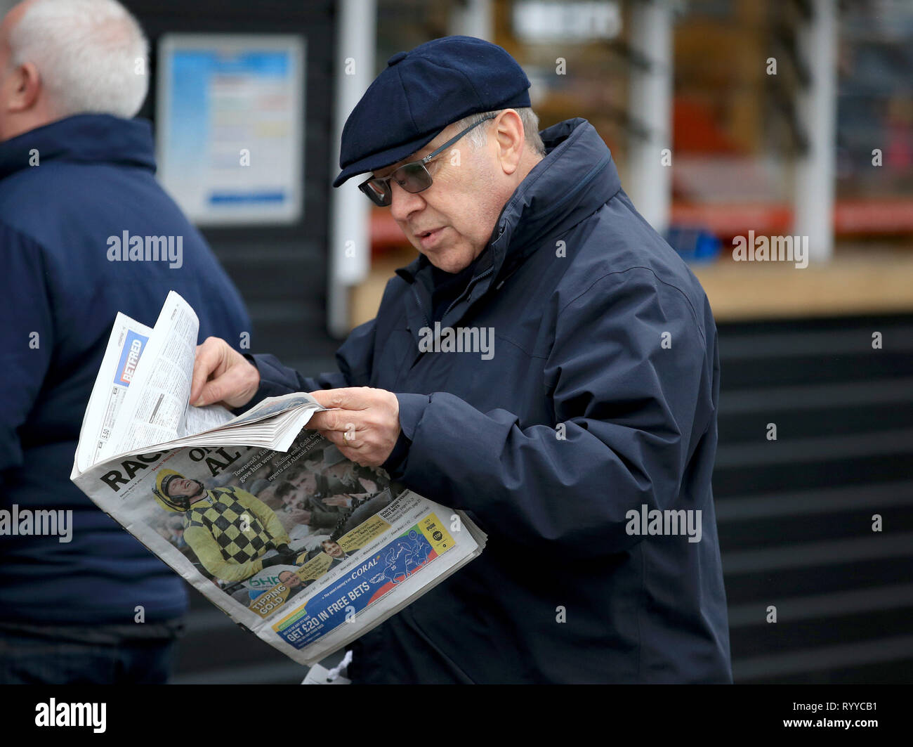 A racegoer reads a copy of The Racing Post paper during the Midlands ...