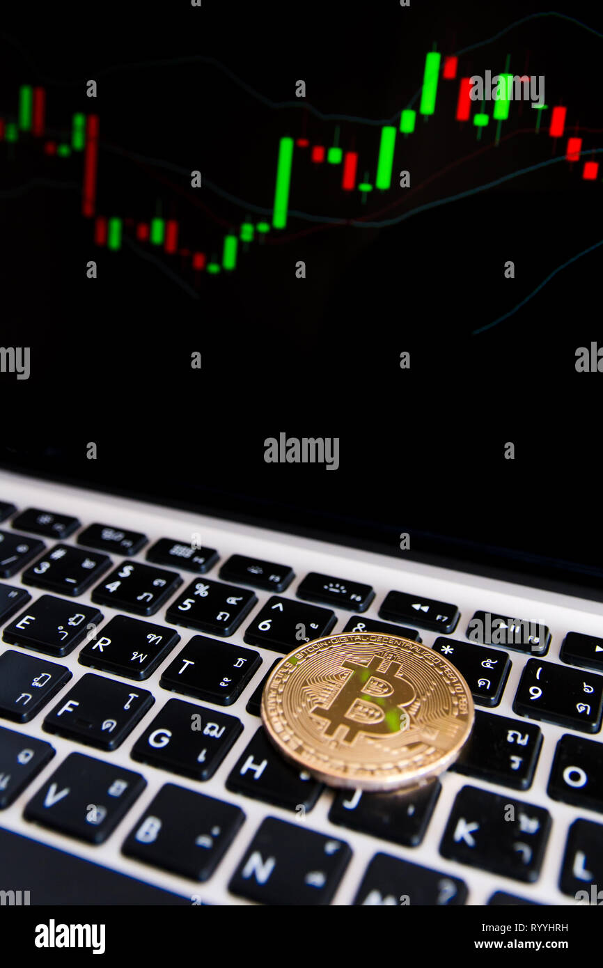 Golden bitcoin coins on keyboard laptop with trading chart background ...