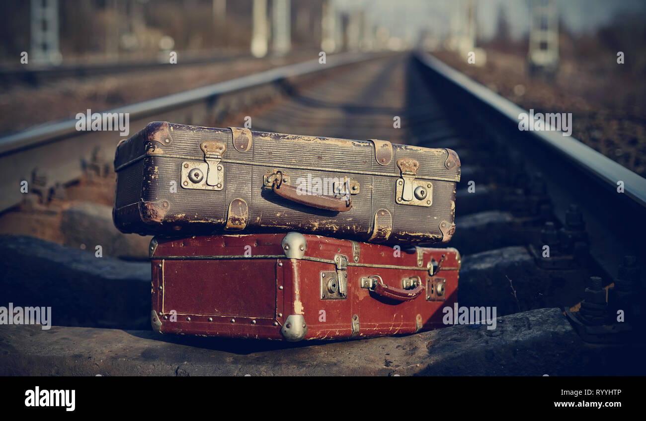 The image of two old vintage suitcases forgotten on railway tracks ...