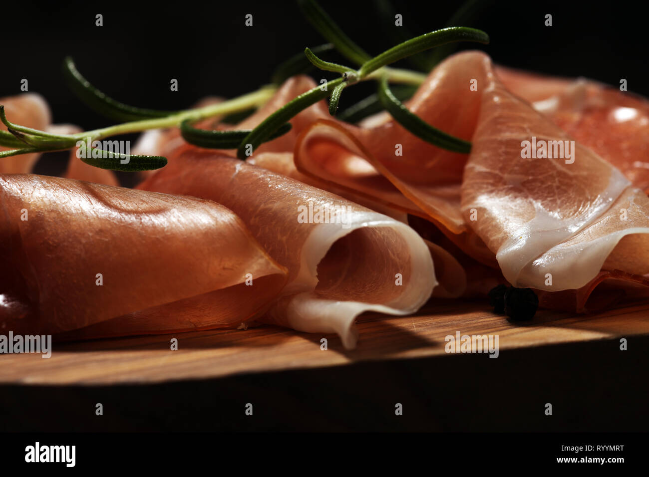 Italian prosciutto crudo or jamon with rosemary. Raw ham on wooden ...