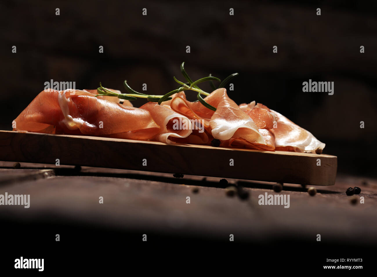 Italian prosciutto crudo or jamon with rosemary. Raw ham on wooden ...