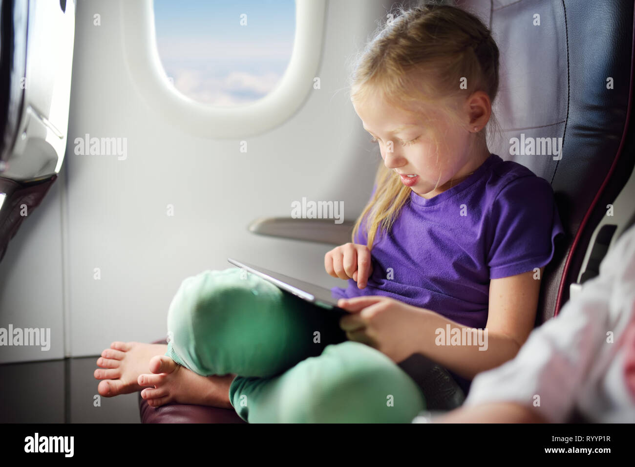 Adorable little girl traveling by an airplane. Child sitting by ...