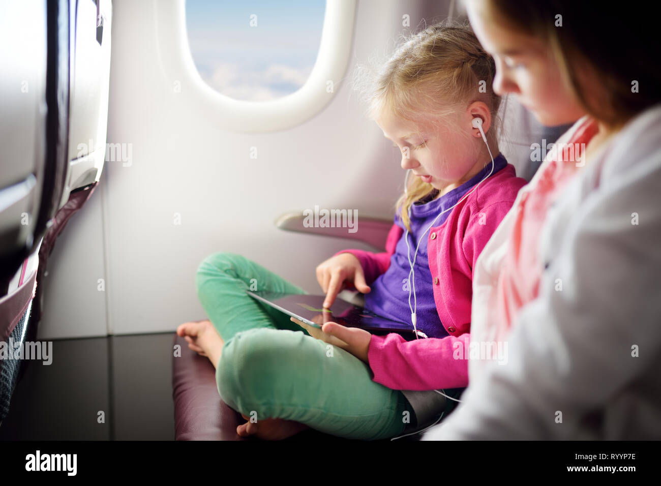 Adorable little girls traveling by an airplane. Children sitting by ...