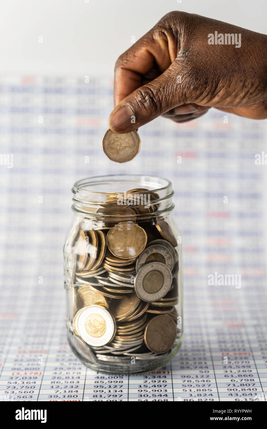 African American Nigerian woman dropping coins into RRSP jar Stock ...