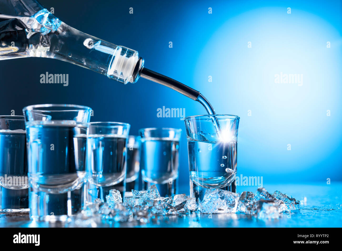 Vodka poured into a glass lit with blue backlight. Chilled vodka with ...