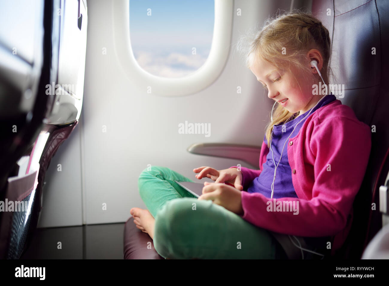 Adorable little girl traveling by an airplane. Child sitting by ...
