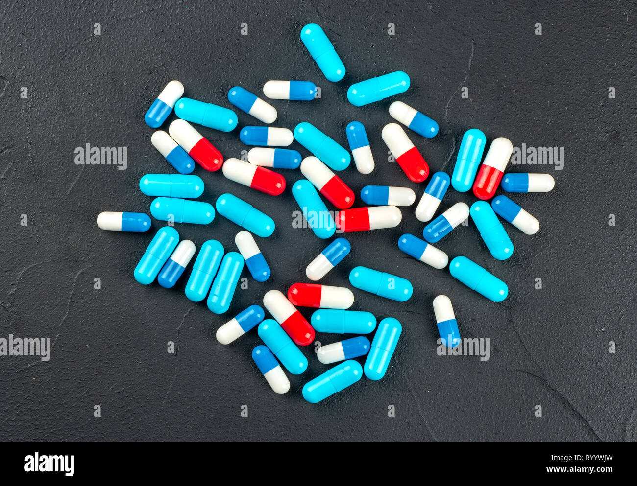 Scattered multicolored capsules on a concrete background, top view ...