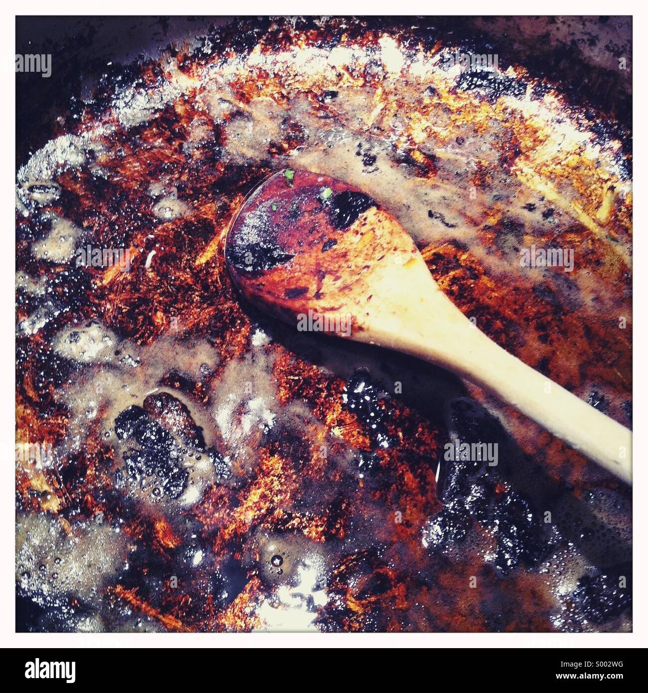 A greasy cooking pan with a wooden spoon Stock Photo - Alamy