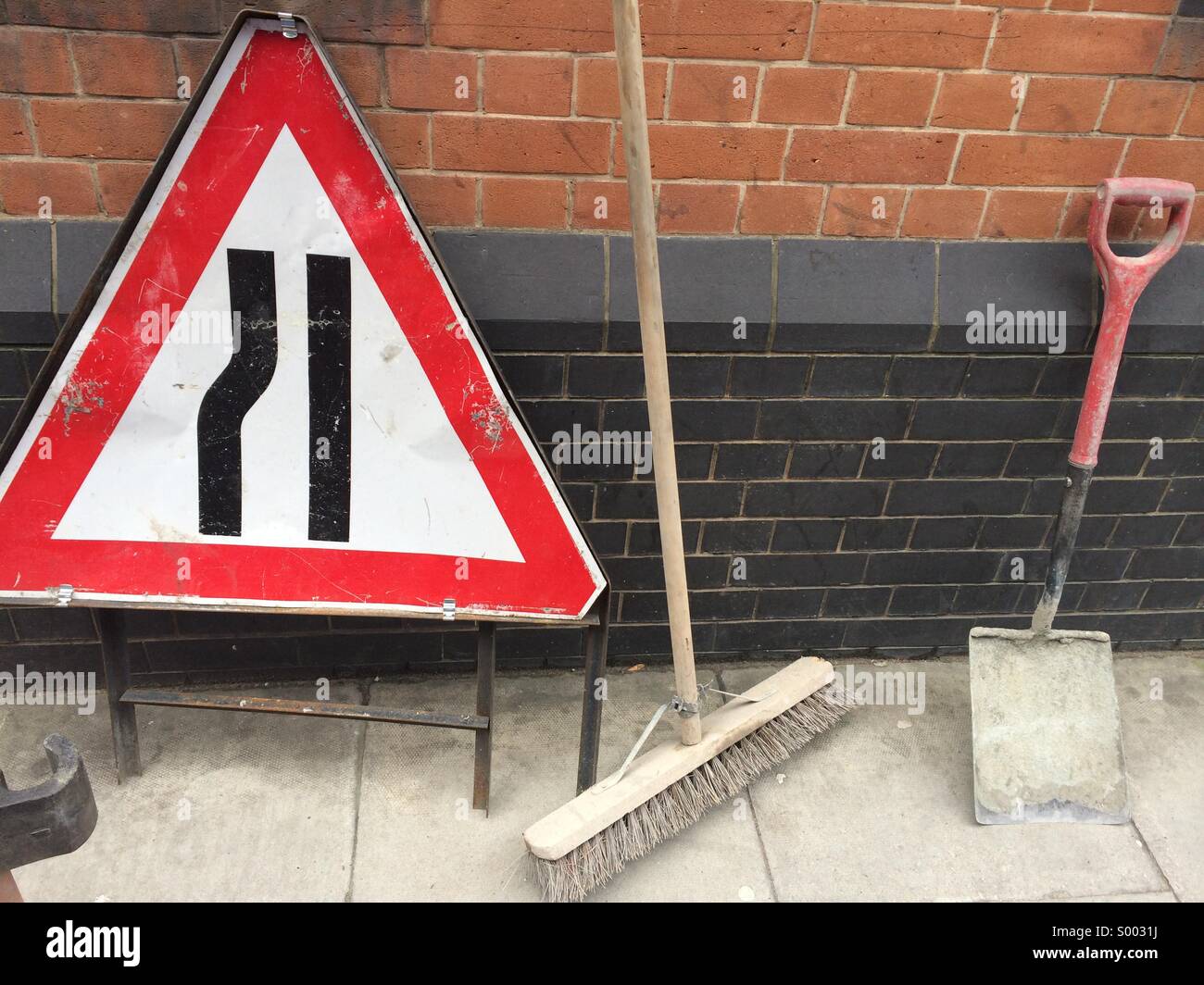 Road sign, broom and spade against a wall Stock Photo - Alamy