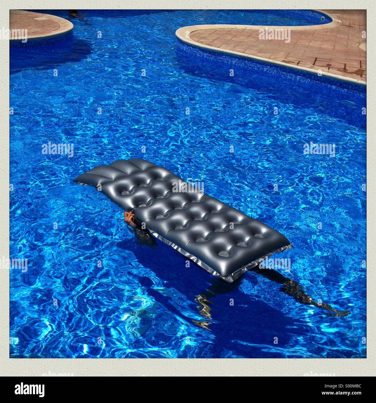 Boy swimming under inflatable mattress in swimming pool Stock Photo - Alamy