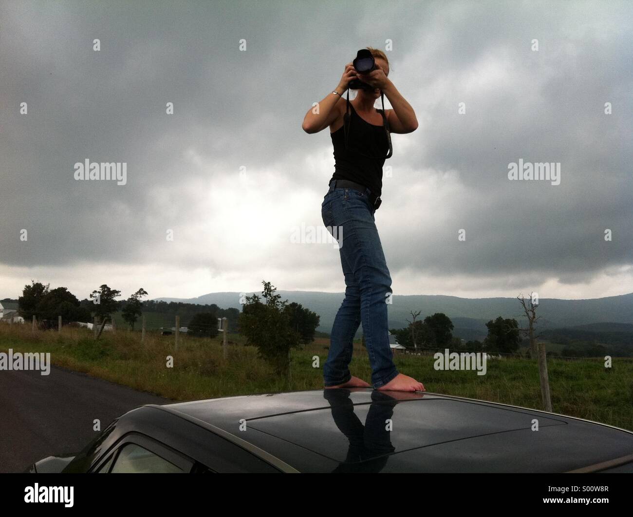 Woman taking photos from roof of car Stock Photo - Alamy