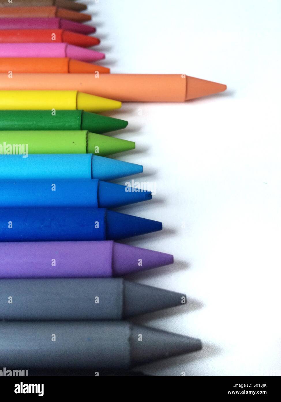 Diagonal of crayons, orange standing out Stock Photo - Alamy