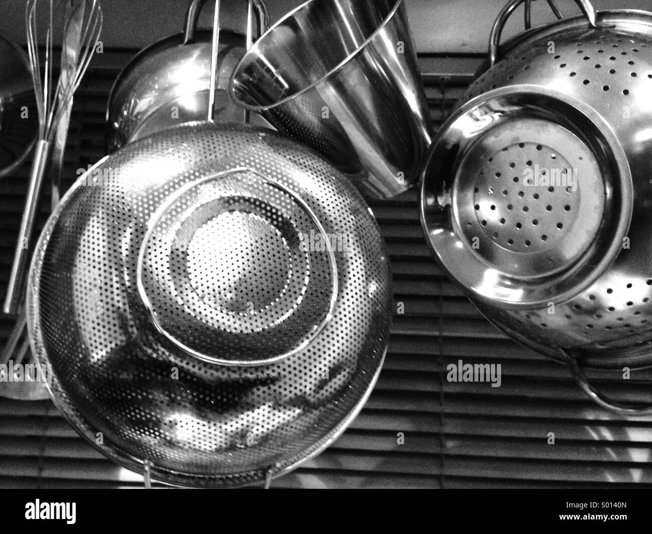 Chrome Kitchen utensils hanging Stock Photo - Alamy