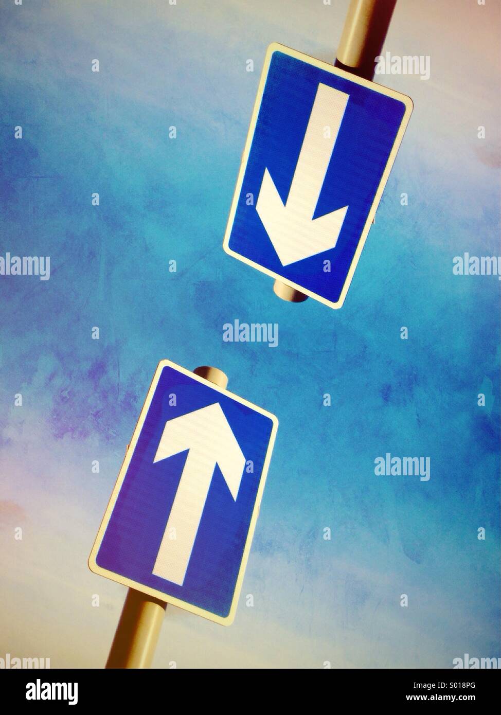 Two one way signs against mottled blue sky Stock Photo - Alamy