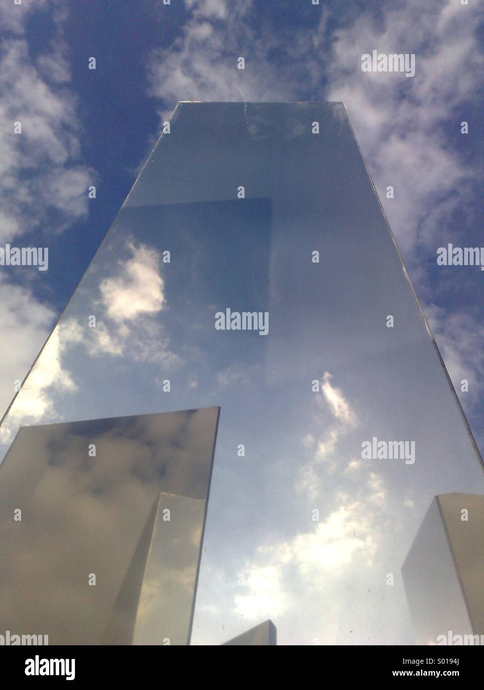 Metal object reflecting a blue sky with clouds Stock Photo - Alamy