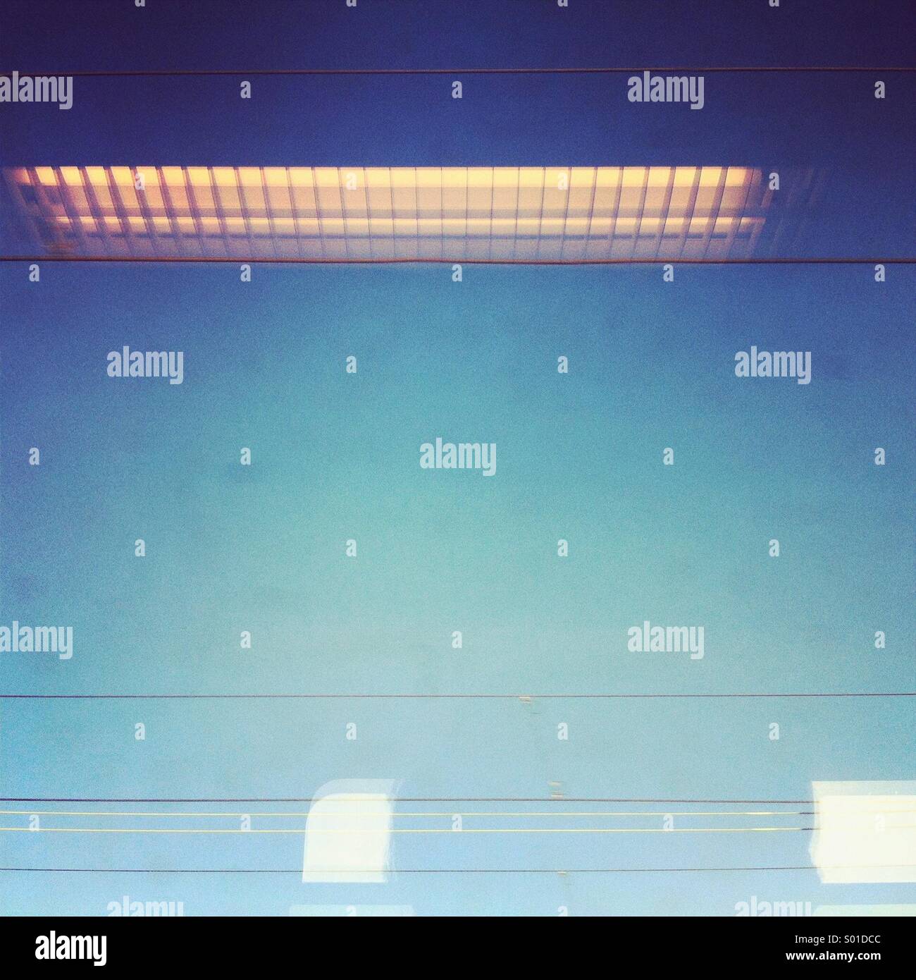 View through a train window of clear blue sky and power lines, with a ...