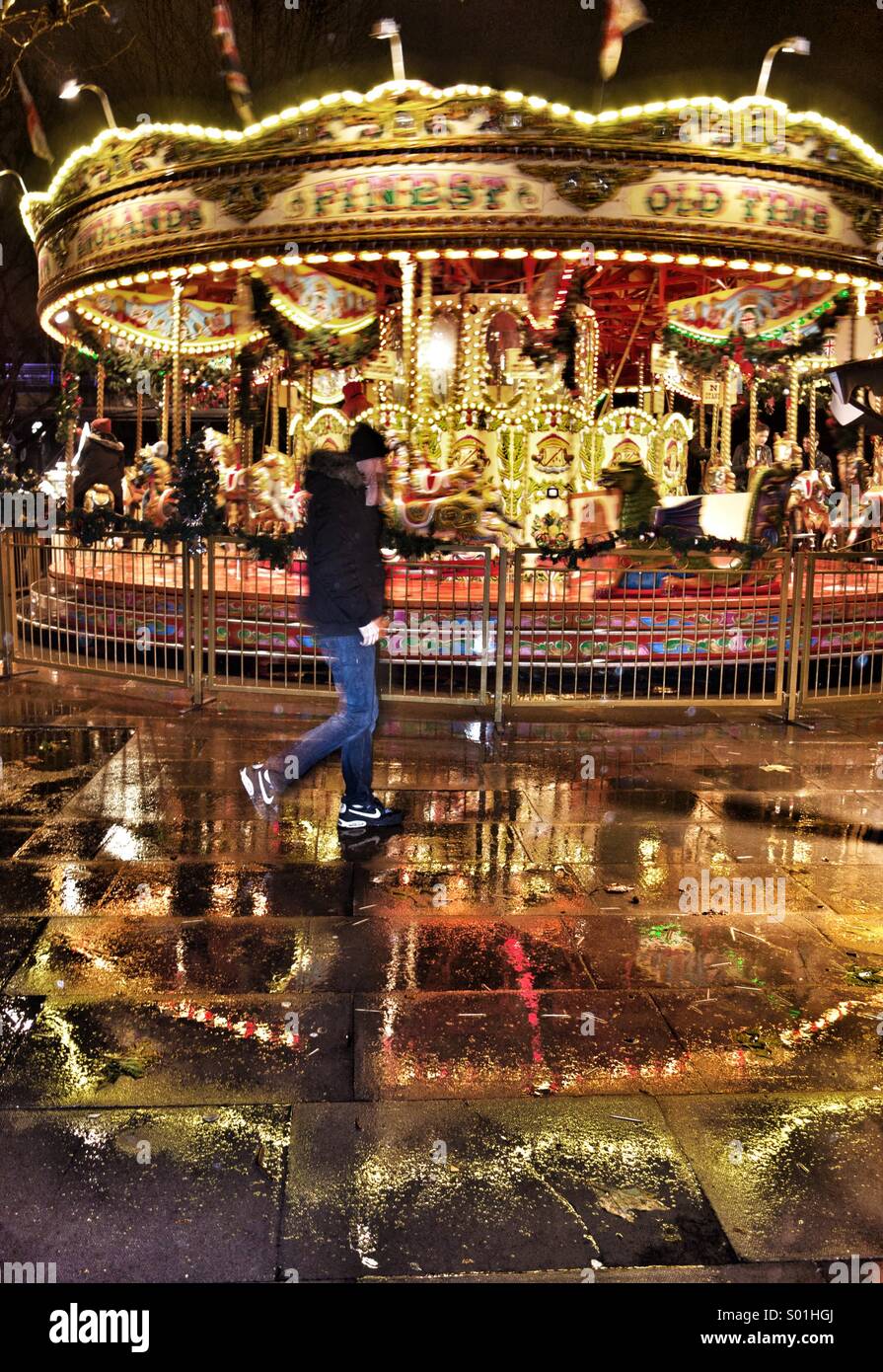 Brightly lit carousel fairground ride at night in the rain Stock Photo ...