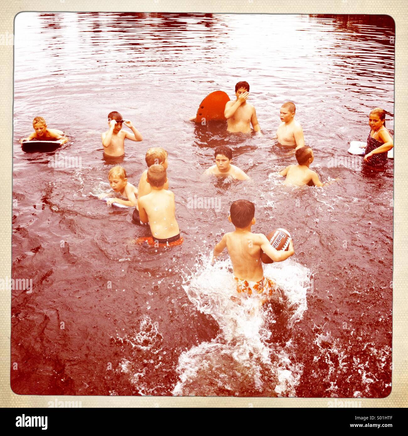Boy running into a pond carrying a football Stock Photo - Alamy
