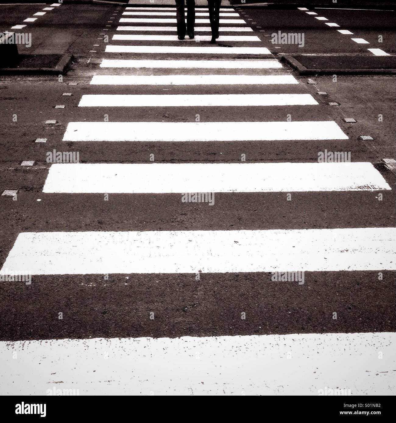 Two people crossing zebra crossing Stock Photo - Alamy
