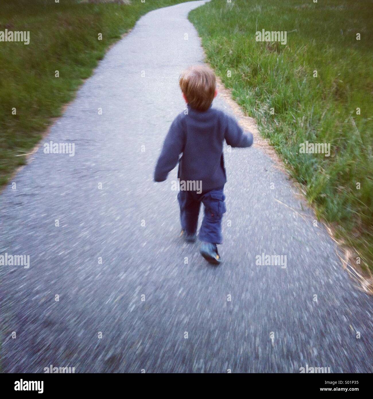 Little boy running down a path lined with grass Stock Photo - Alamy
