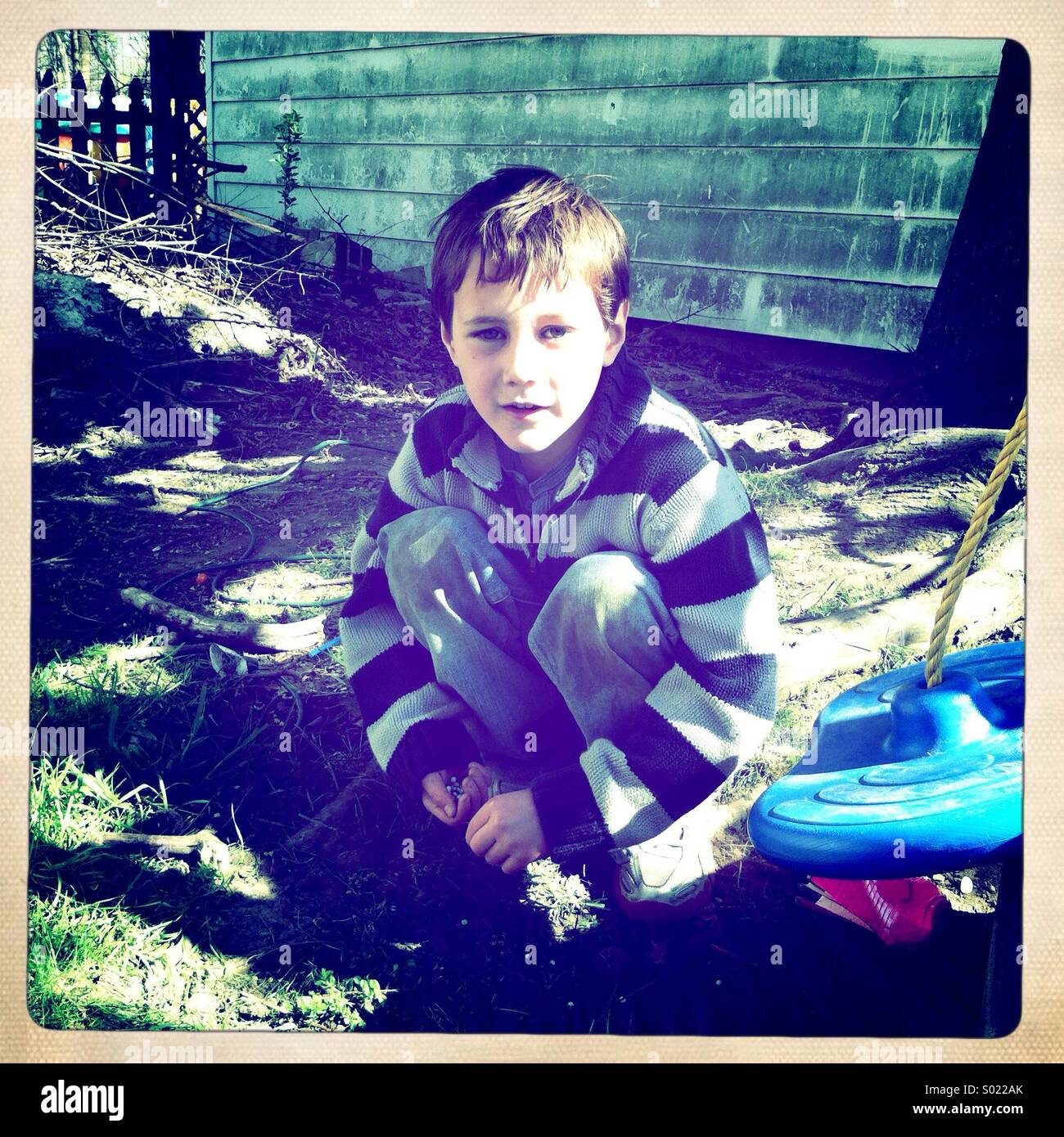 Boy crouched down outside Stock Photo - Alamy