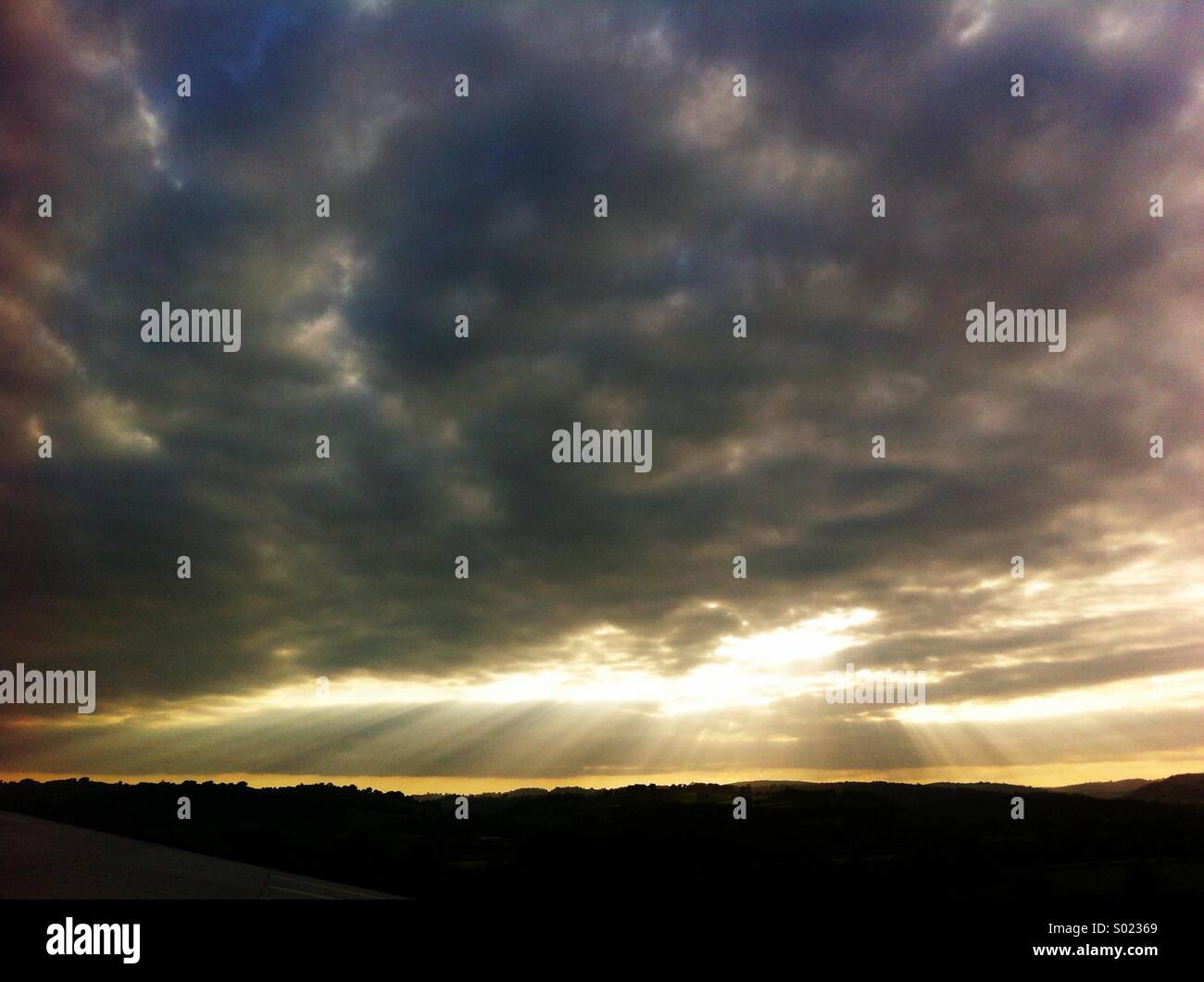Sun rays through clouds at sunset Stock Photo - Alamy