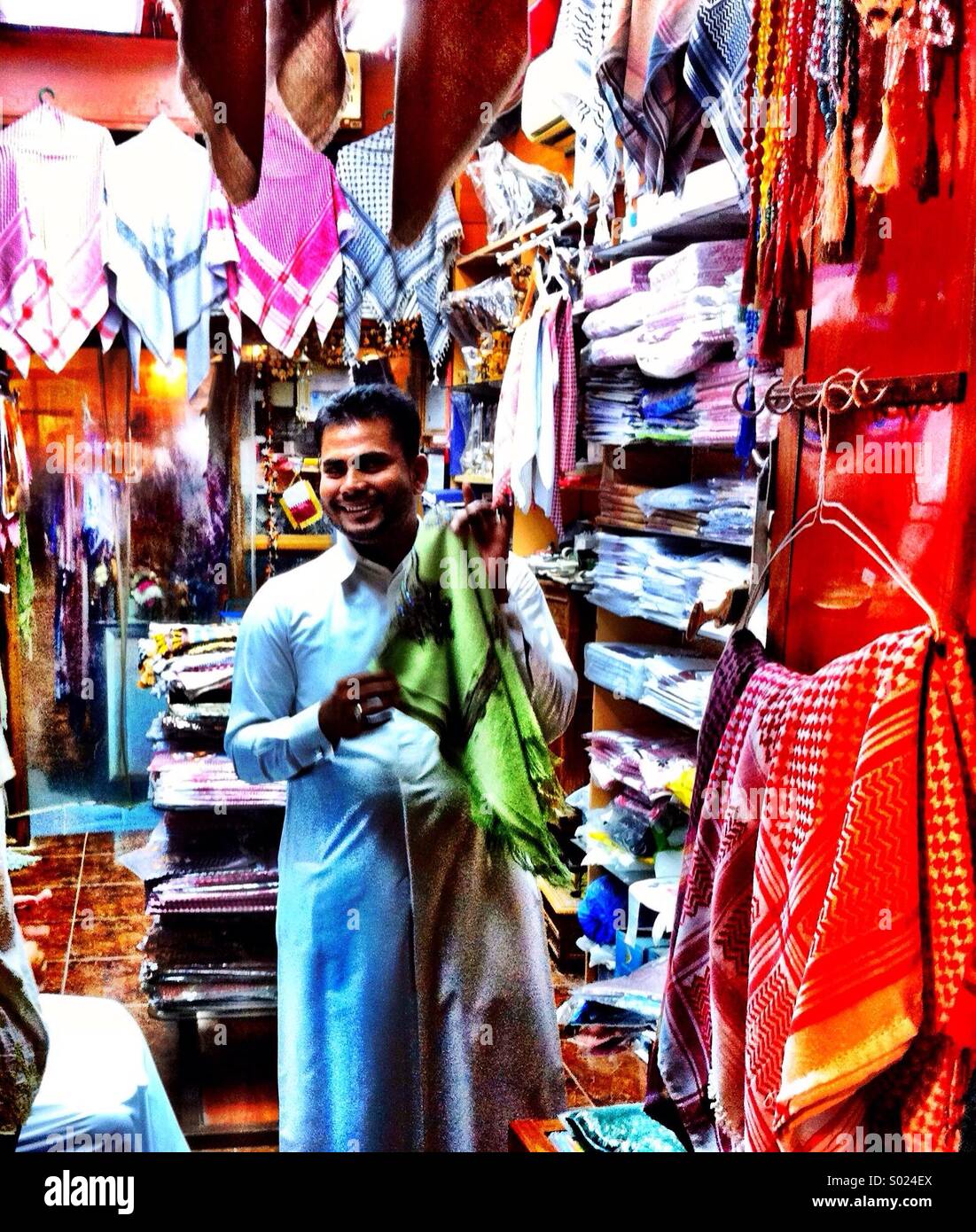 Smiling cloth salesman in Arab souk invites customers to inspect his ...