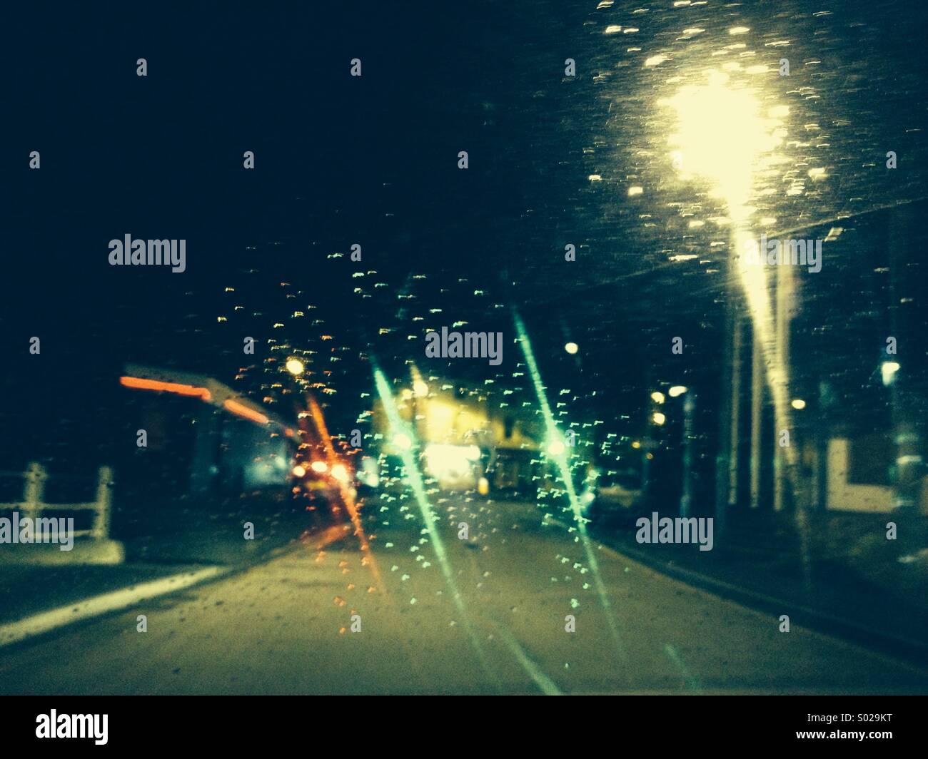 Bright coloured lights refracting through rain drops on a car ...