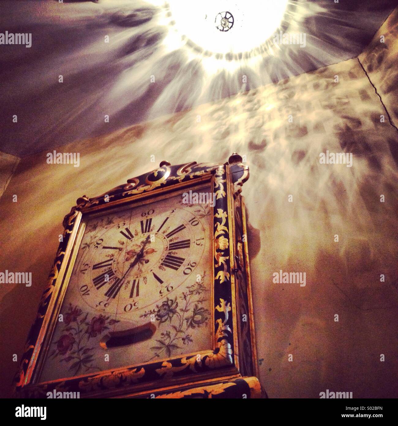 Old clock on a wall lit by a lamp Stock Photo - Alamy