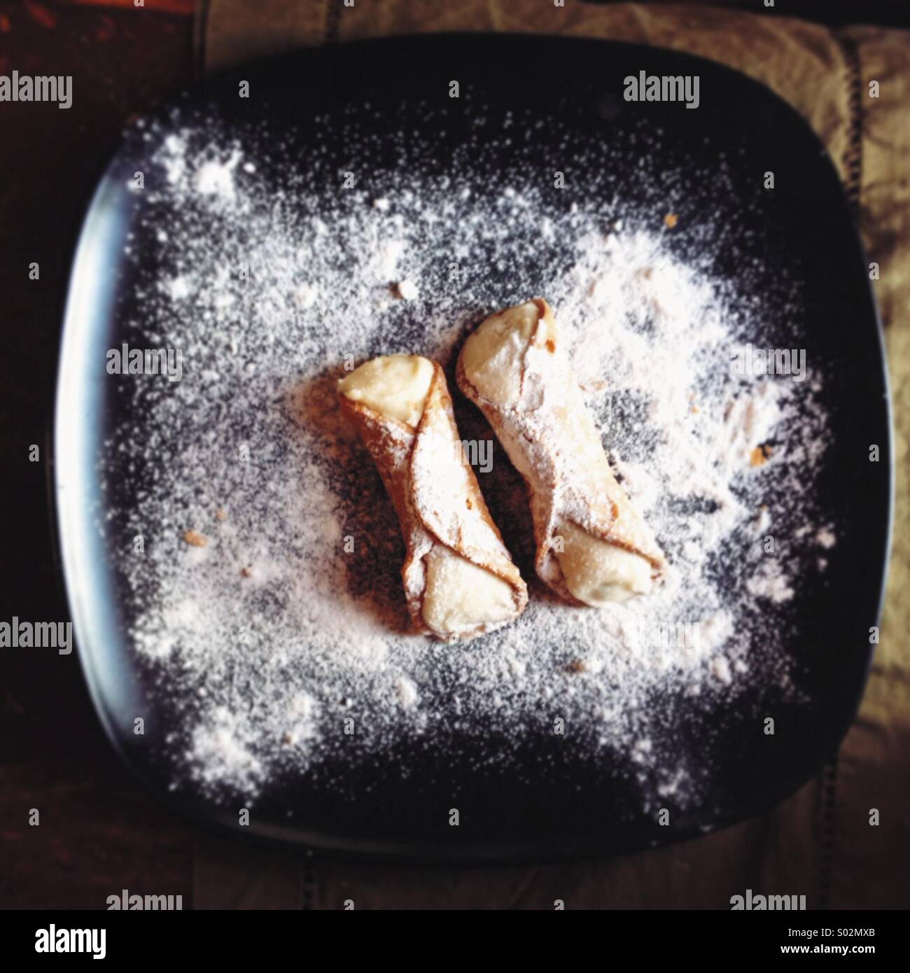 Two cannoli on a black plate Stock Photo - Alamy