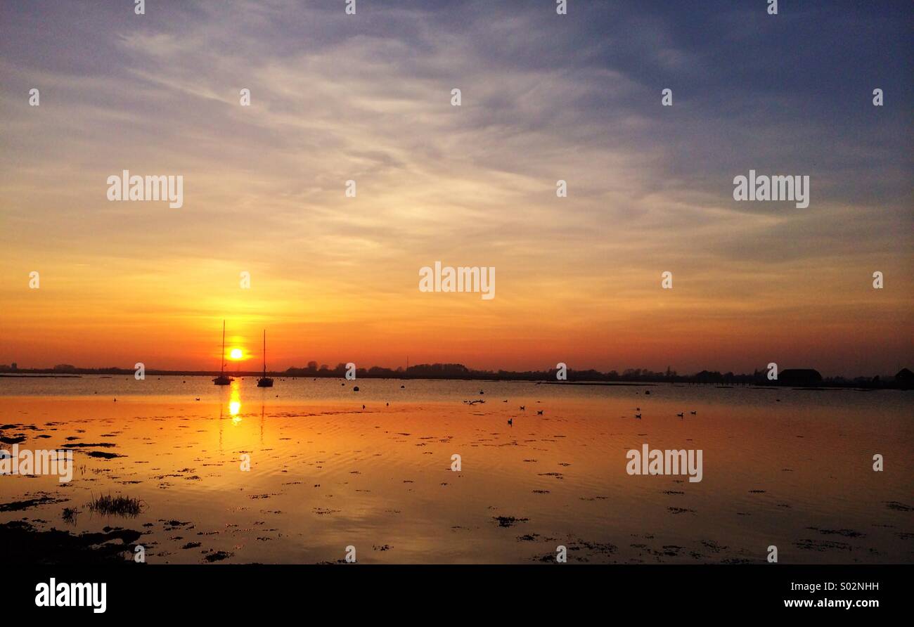Sun setting over English village harbour with sailing yachts in the ...