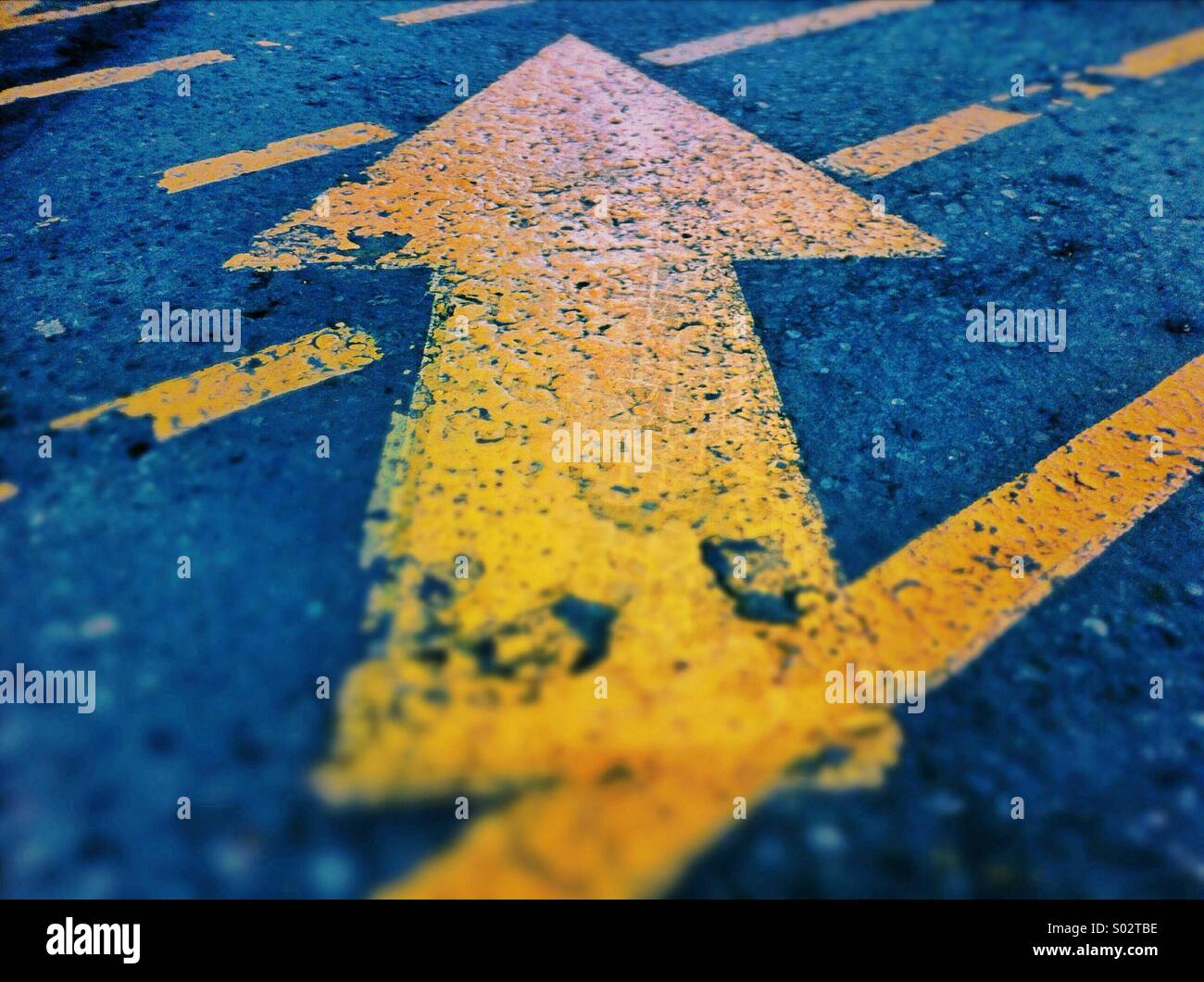 Yellow directional arrow painted on pavement inside a covered parking ...