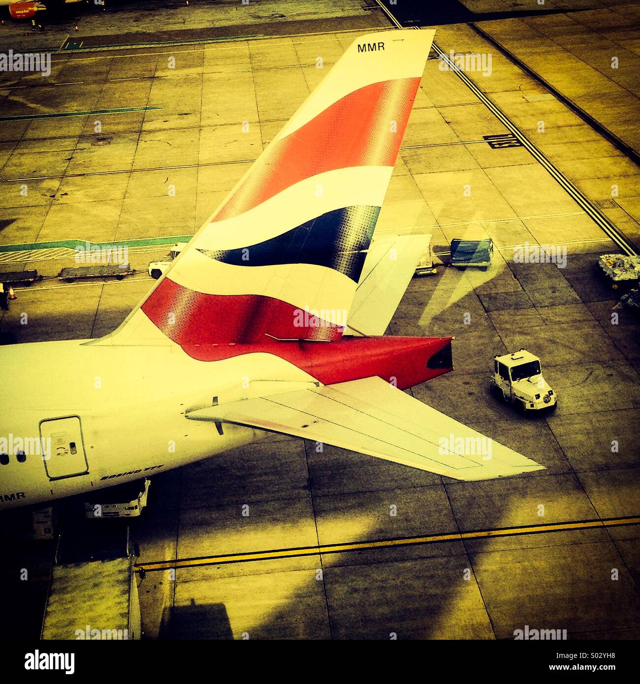 Tail of British Airways plane with ground support vehicles at north ...