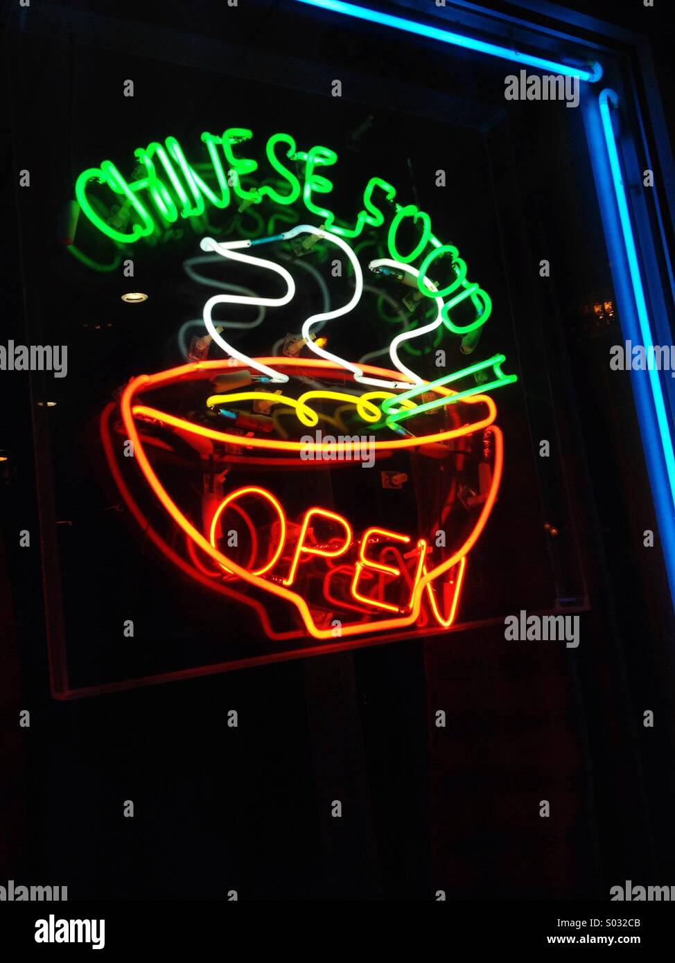 A colorful neon Chinese food restaurant sign on a window glows warmly ...