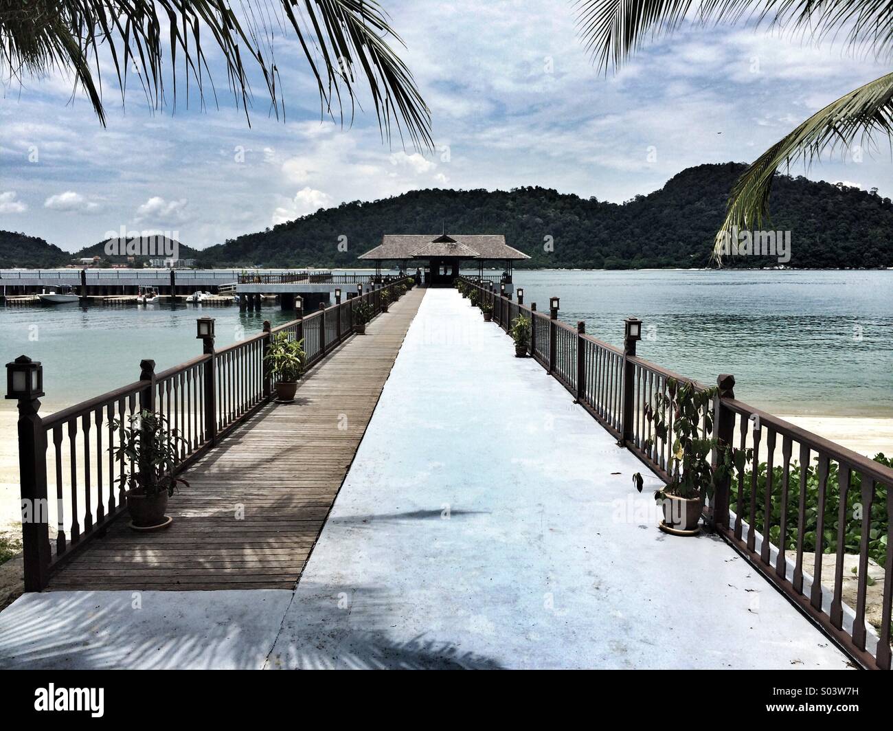 Concrete Jetty walkway with a hilly background in a tropical island ...