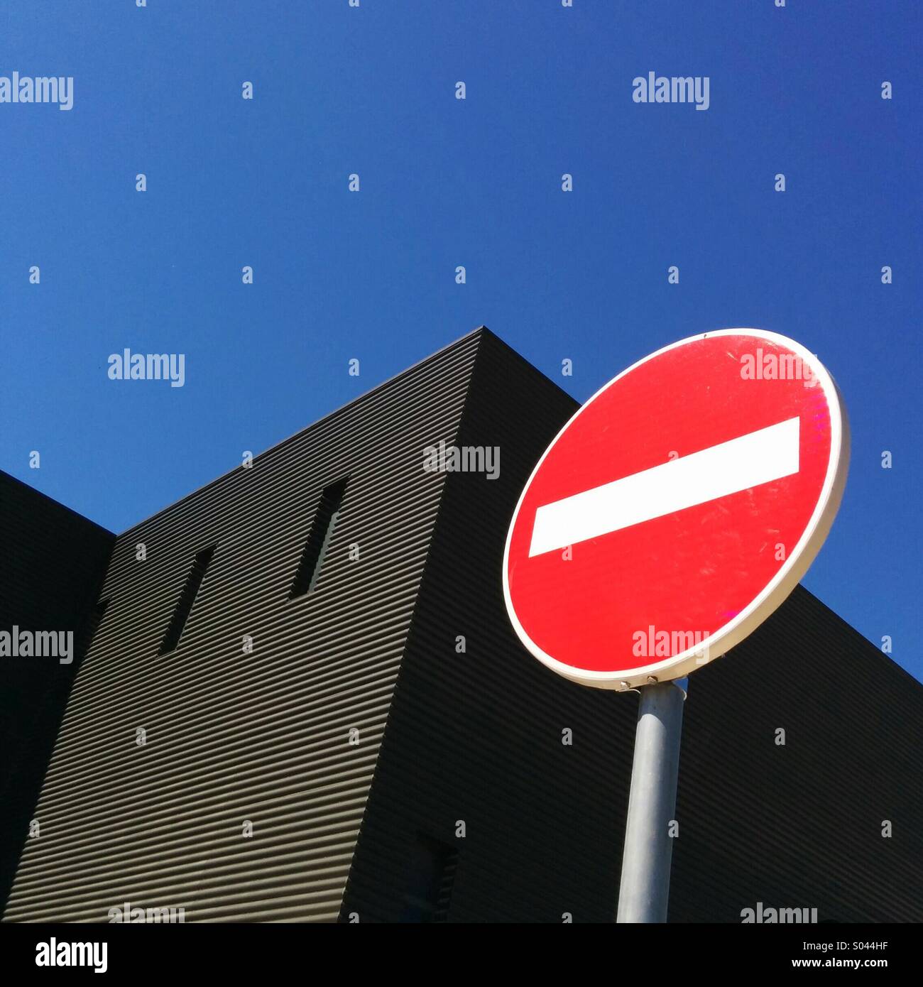 No entry sign against a blue sky and modern black building Stock Photo ...