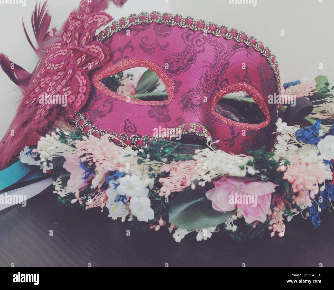 Red cloth masquerade mask resting on a wreath of dried flowers set ...