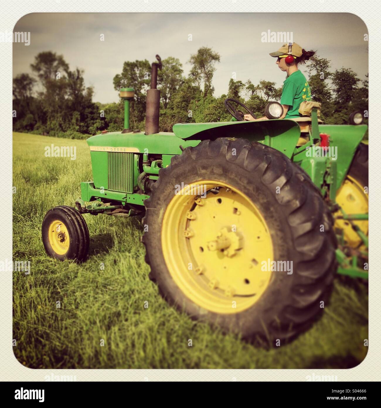 Girl driving tractor in farm field Stock Photo - Alamy